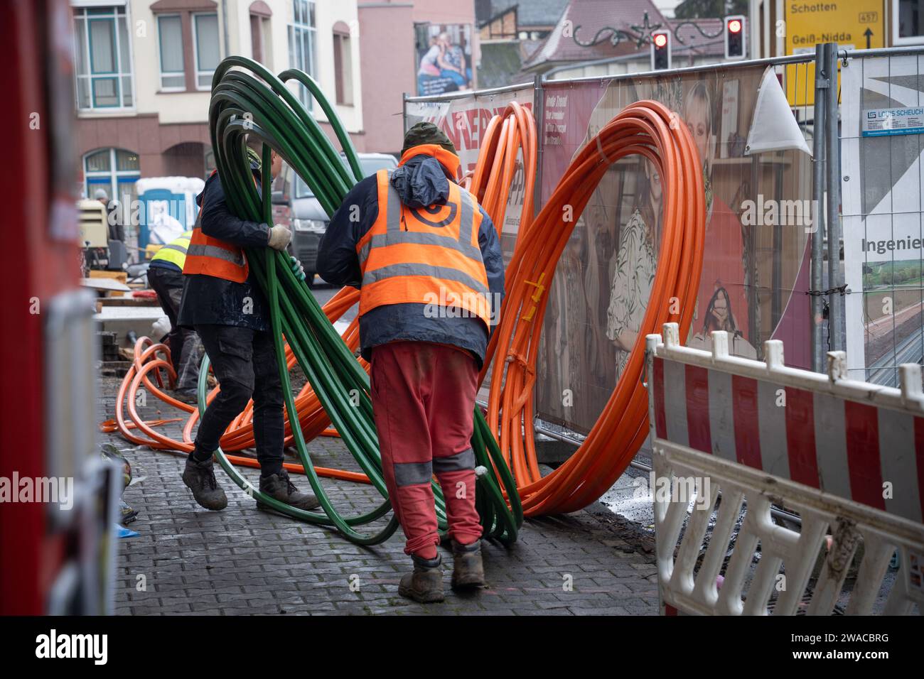 Nidda, Germany. 24th Nov, 2023. Workers lay the sheaths for fiber optic ...