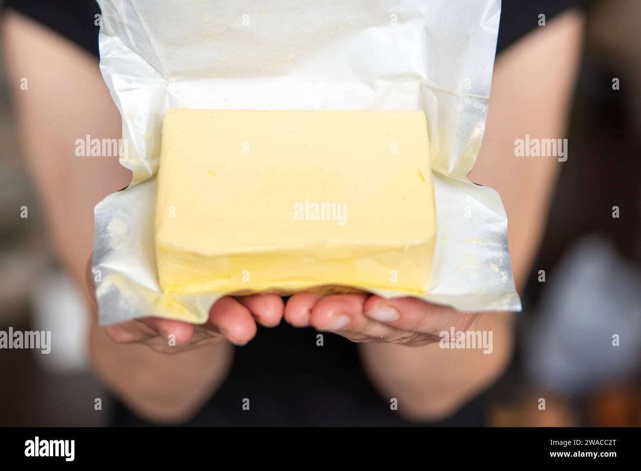 A hand holds butter in a pack close-up. Process of making sandwiches ...