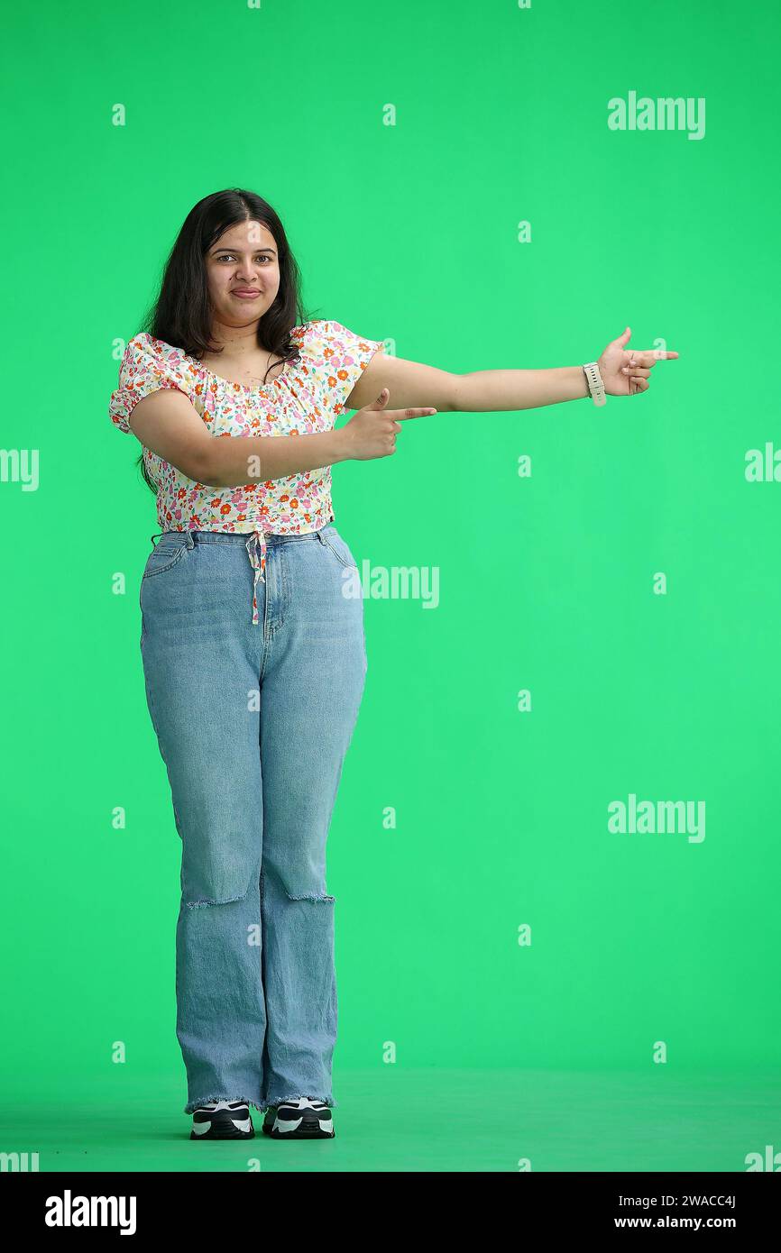 A woman, on a green background, full-length, points to the side Stock ...