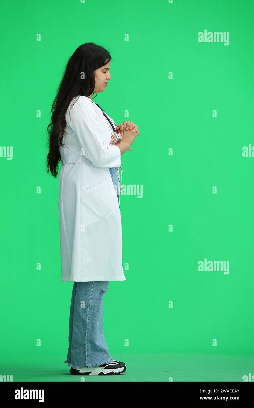 A female doctor, on a green background, full-length, dreaming, profile ...
