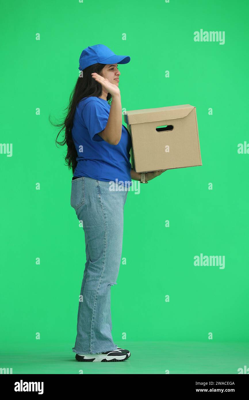 A delivery woman with a box, on a green background, in full height ...