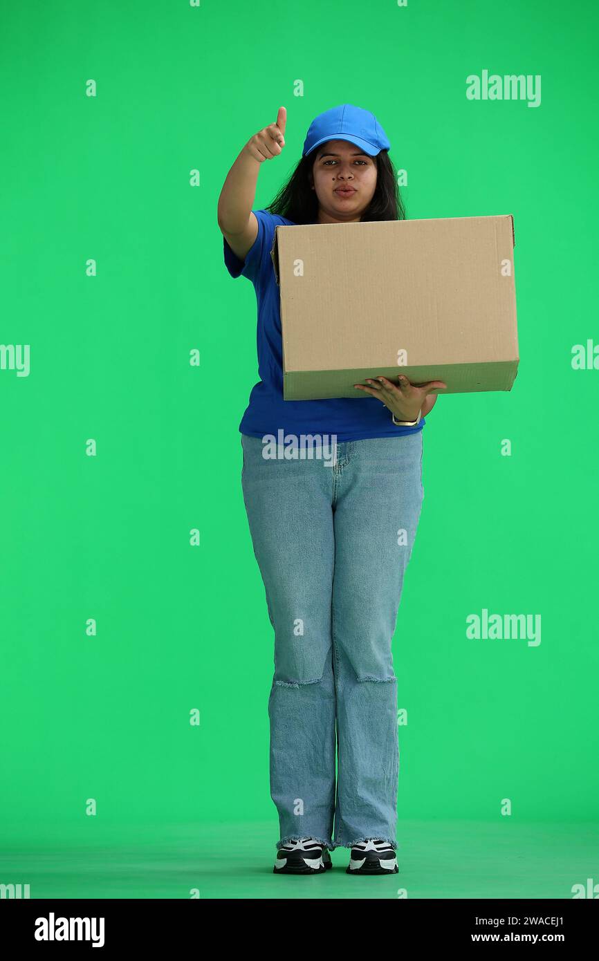 A delivery woman with a box, on a green background, in full height ...