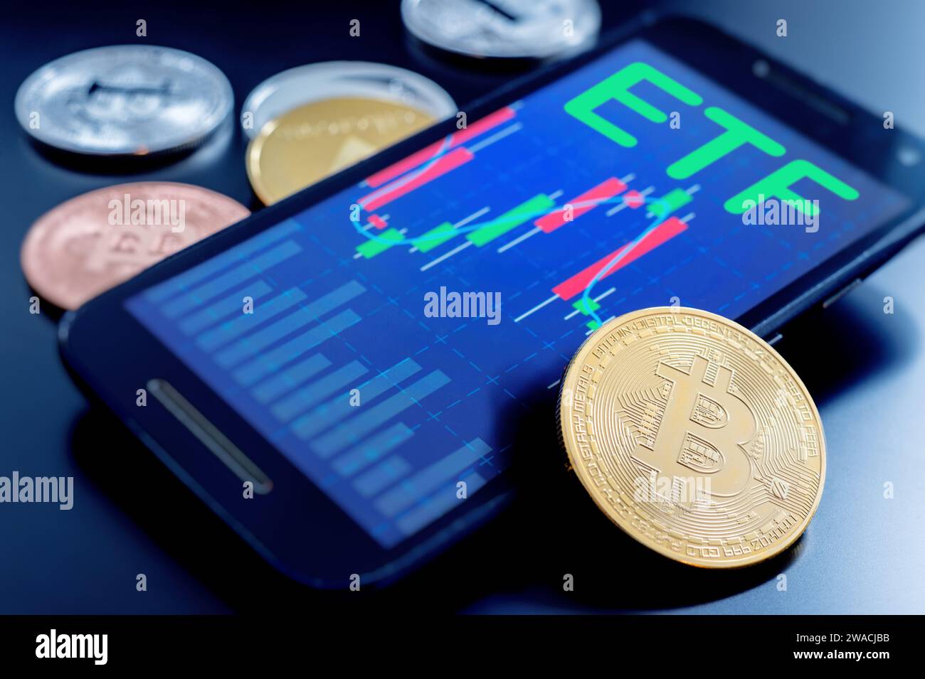Cryptocurrency coins next to a cell phone showing candlestick chart and ...