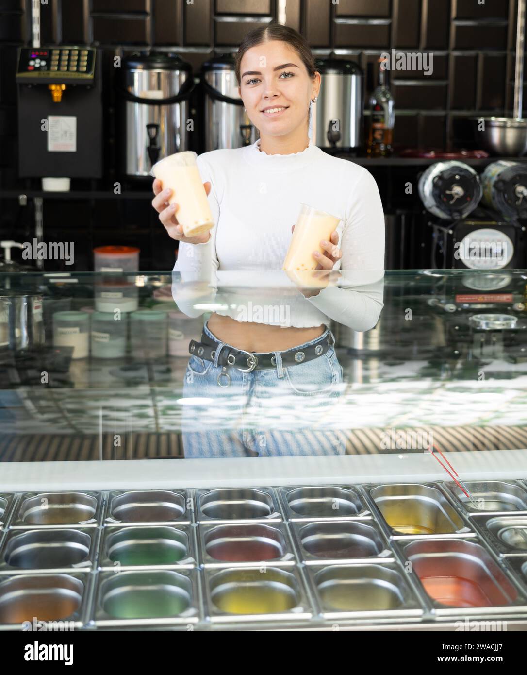 Cheerful young female barista offering refreshing Taiwanese bubble tea ...