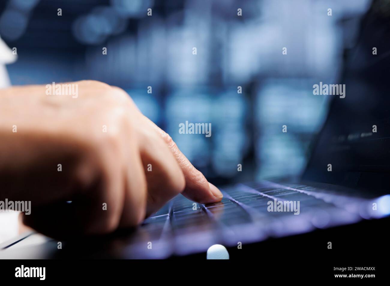 Cloud computing company executive using laptop to examine server racks ...