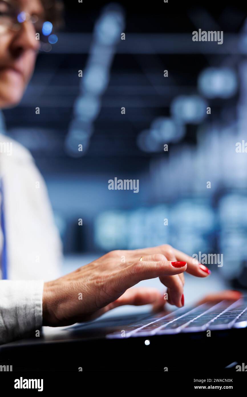 Old IT expert in server farm using laptop, ensuring valuable data ...