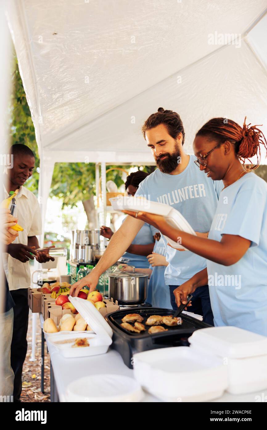 Young black woman and caucasian man cook and donate free meal at a food ...