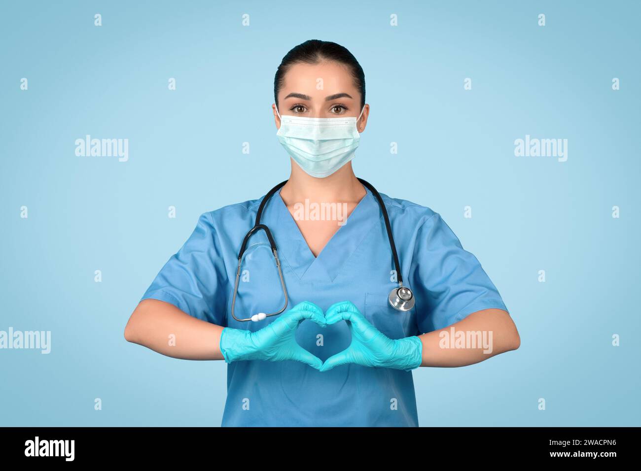 Caring nurse with heart hands, blue scrubs Stock Photo - Alamy