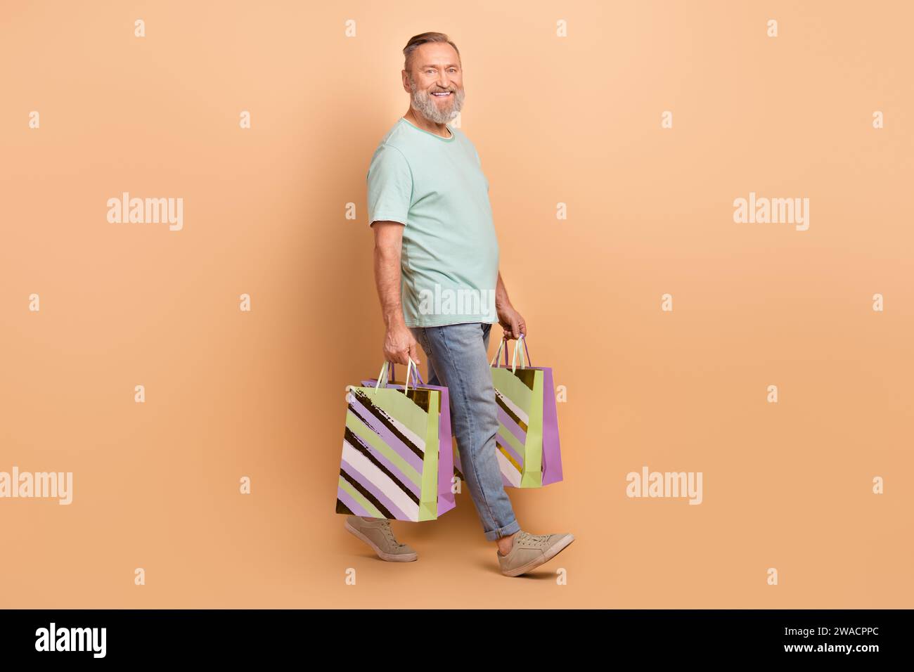 Full body profile portrait of cheerful aged man hold mall bags walk ...