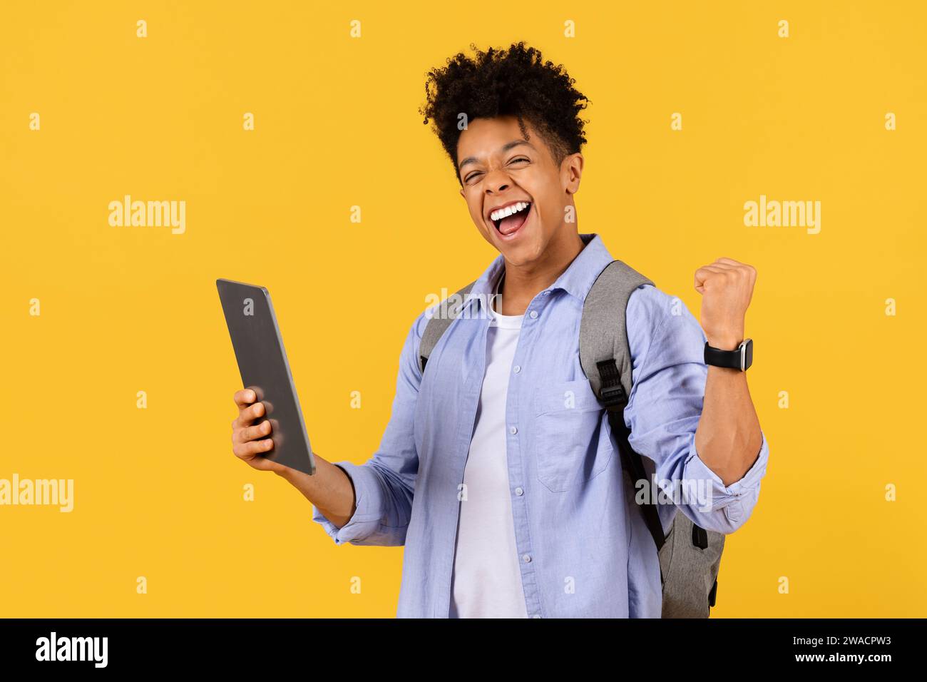 Exuberant black male student with tablet celebrating on yellow Stock ...