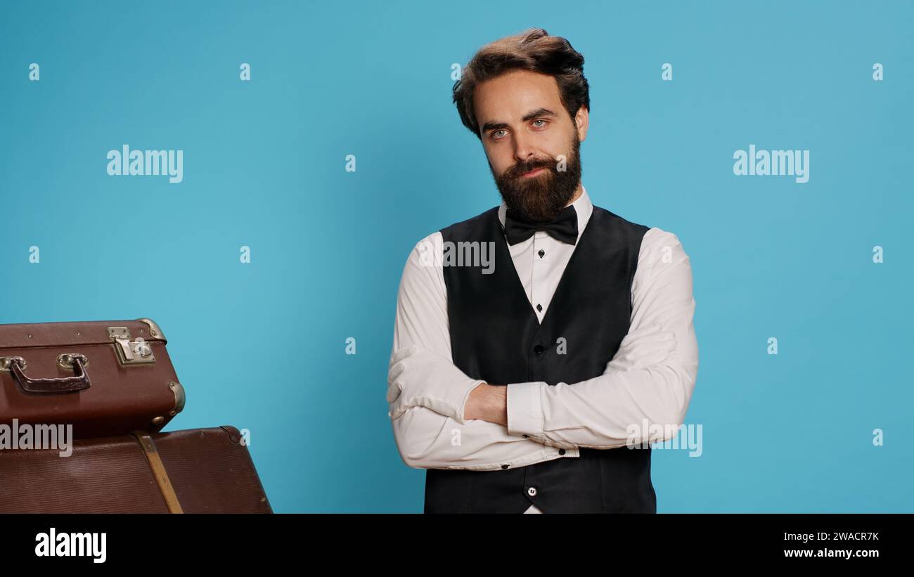 Experienced confident bellhop in studio, wearing formal hotel lobby ...