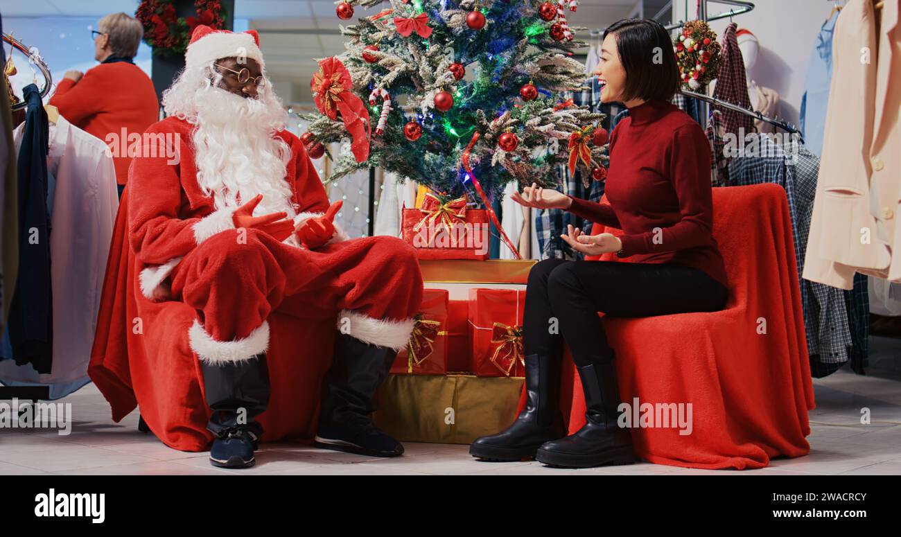 Dolly out shot of worker acting as Santa Claus sitting down next to ...