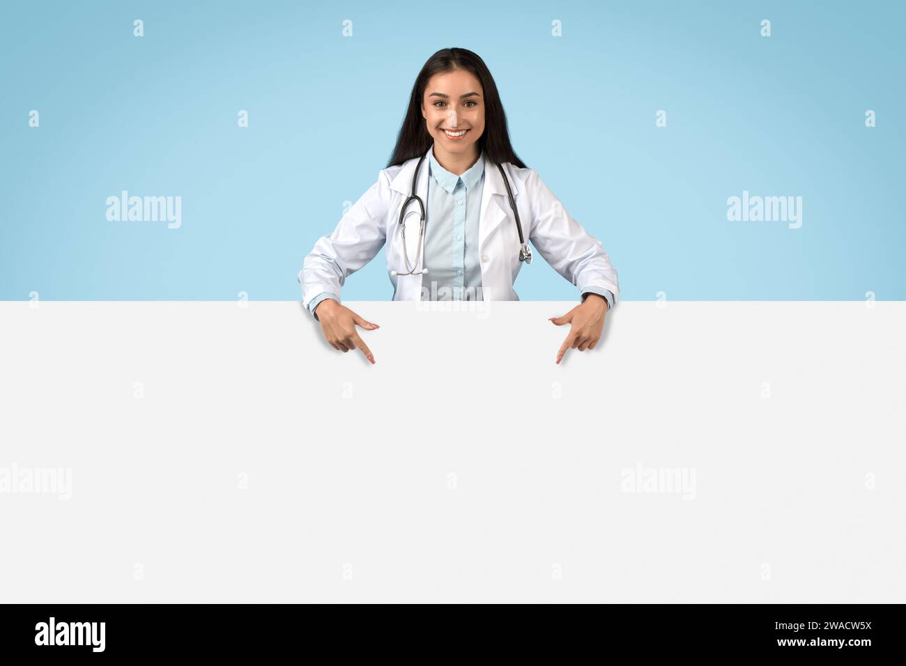 Woman doctor pointing at an empty banner, happy demeanor Stock Photo ...