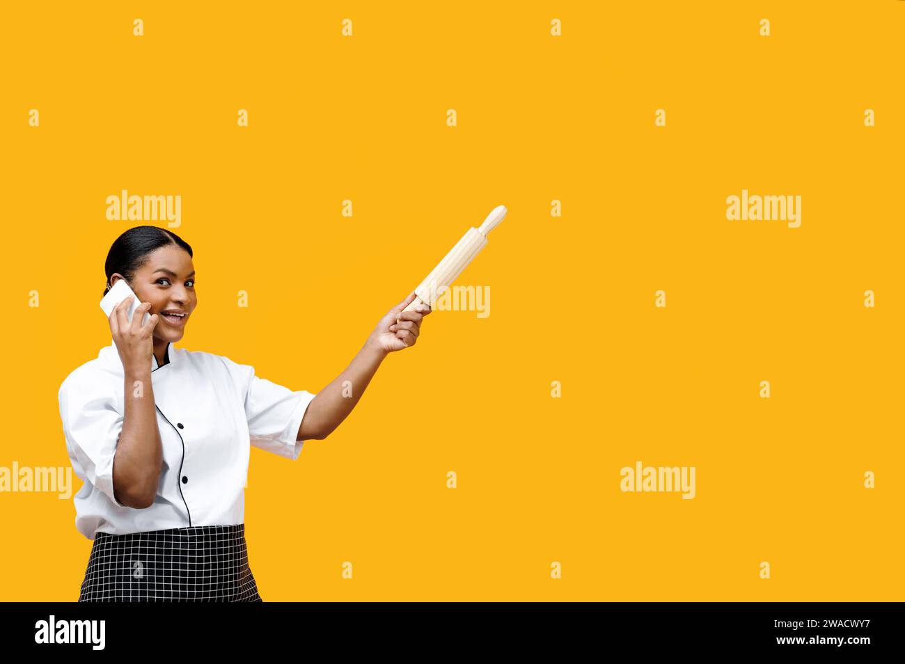 Efficient black female chef managing tasks over phone and holding ...