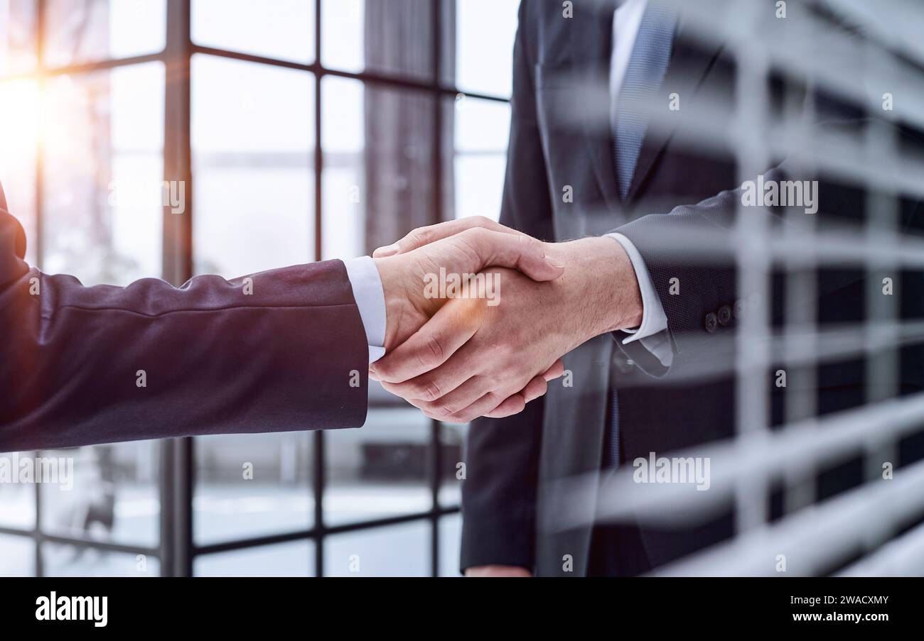 executives shaking hands in front of their manager and a colleague ...