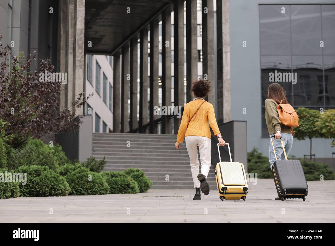 Being late. Women with suitcases walking towards building outdoors ...