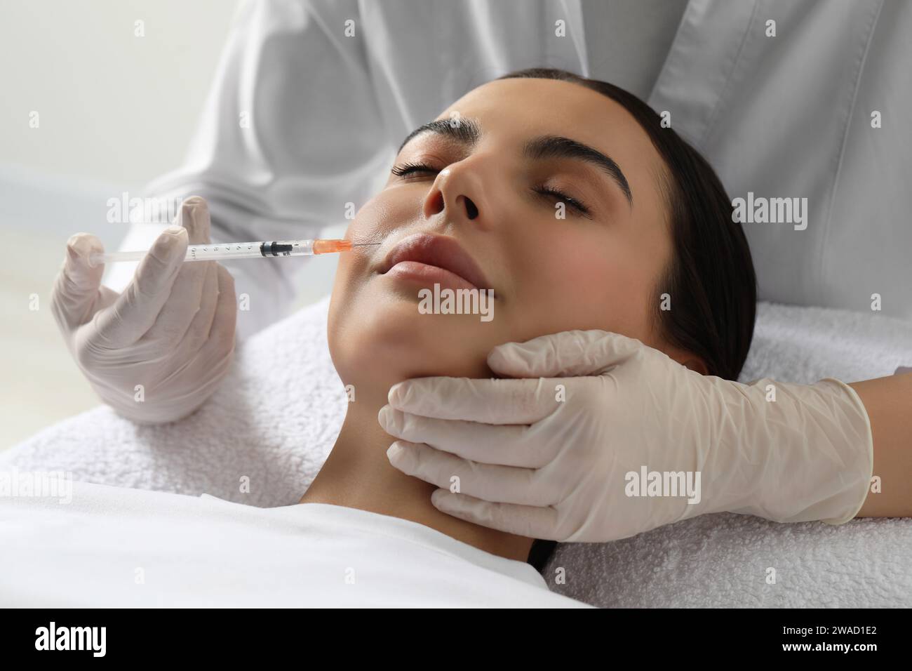 Doctor giving facial injection to young woman in clinic. Cosmetic ...