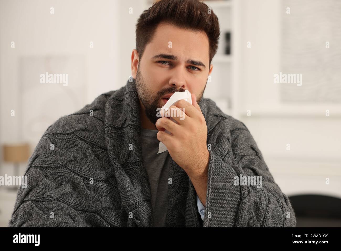 Sick man wrapped in blanket with tissue at home. Cold symptoms Stock ...