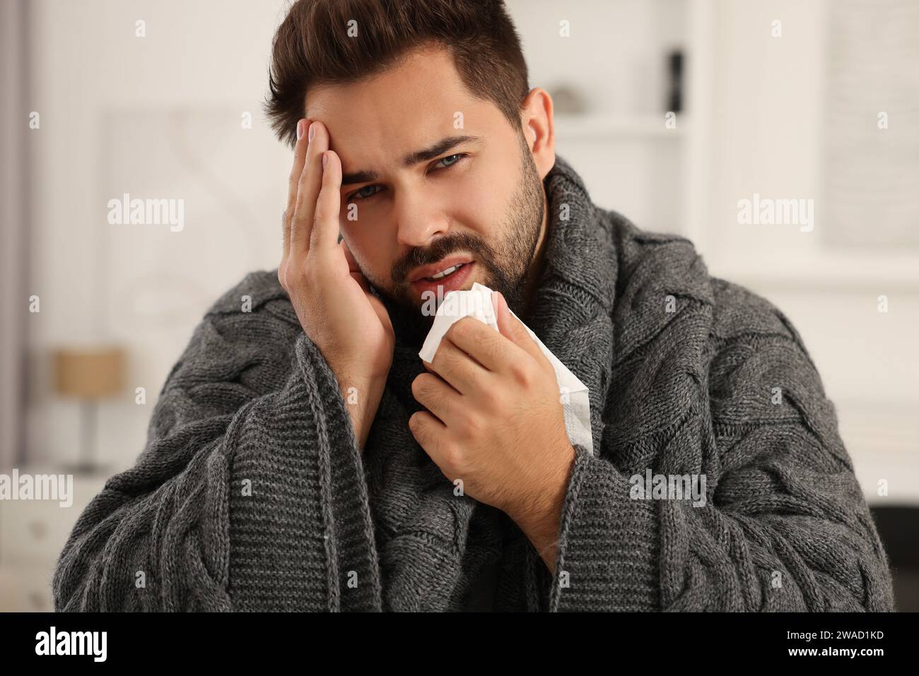 Sick man wrapped in blanket with tissue at home. Cold symptoms Stock ...
