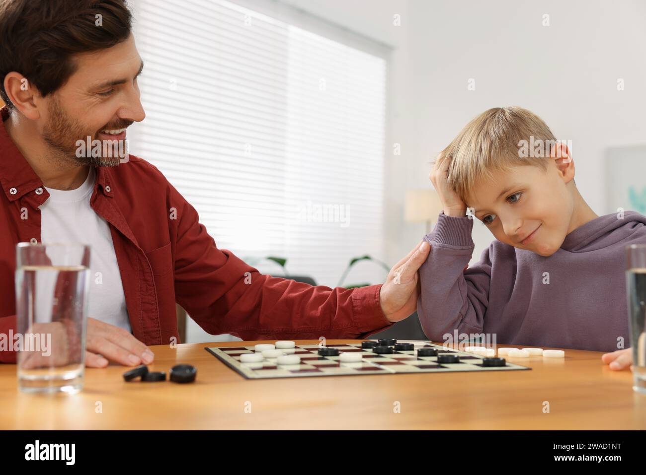 Father cheering his son while they playing checkers in room Stock Photo ...