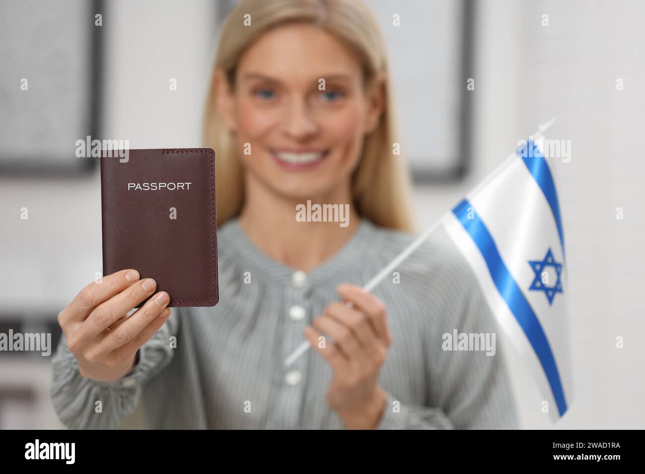 Immigration. Happy woman with passport and flag of Israel indoors ...