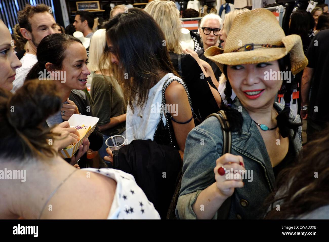 Women in a crowd at a fashion label launch event and party in jeans ...