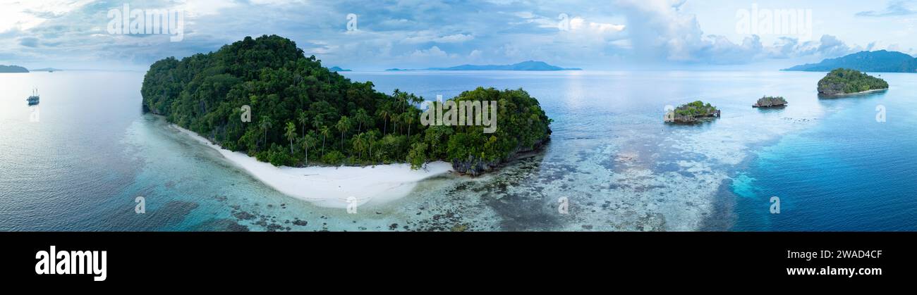 A pristine beach fringes a scenic limestone island in Raja Ampat ...