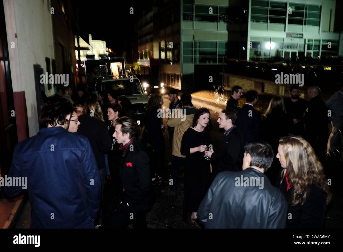 People talking in the street at night outside an art opening event ...