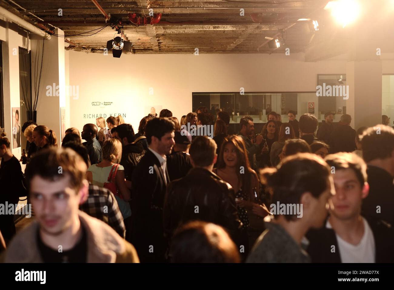 People attending a Richard Kern art opening in Sydney, looking across a ...