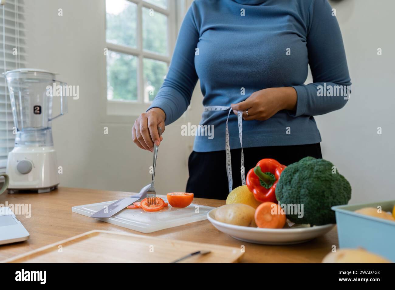 Overweight woman measuring her hip with tape measure while eating ...