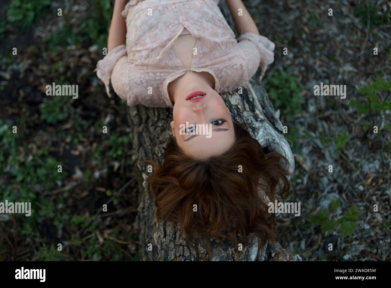 Portrait of serious woman lying on tree trunk Stock Photo - Alamy