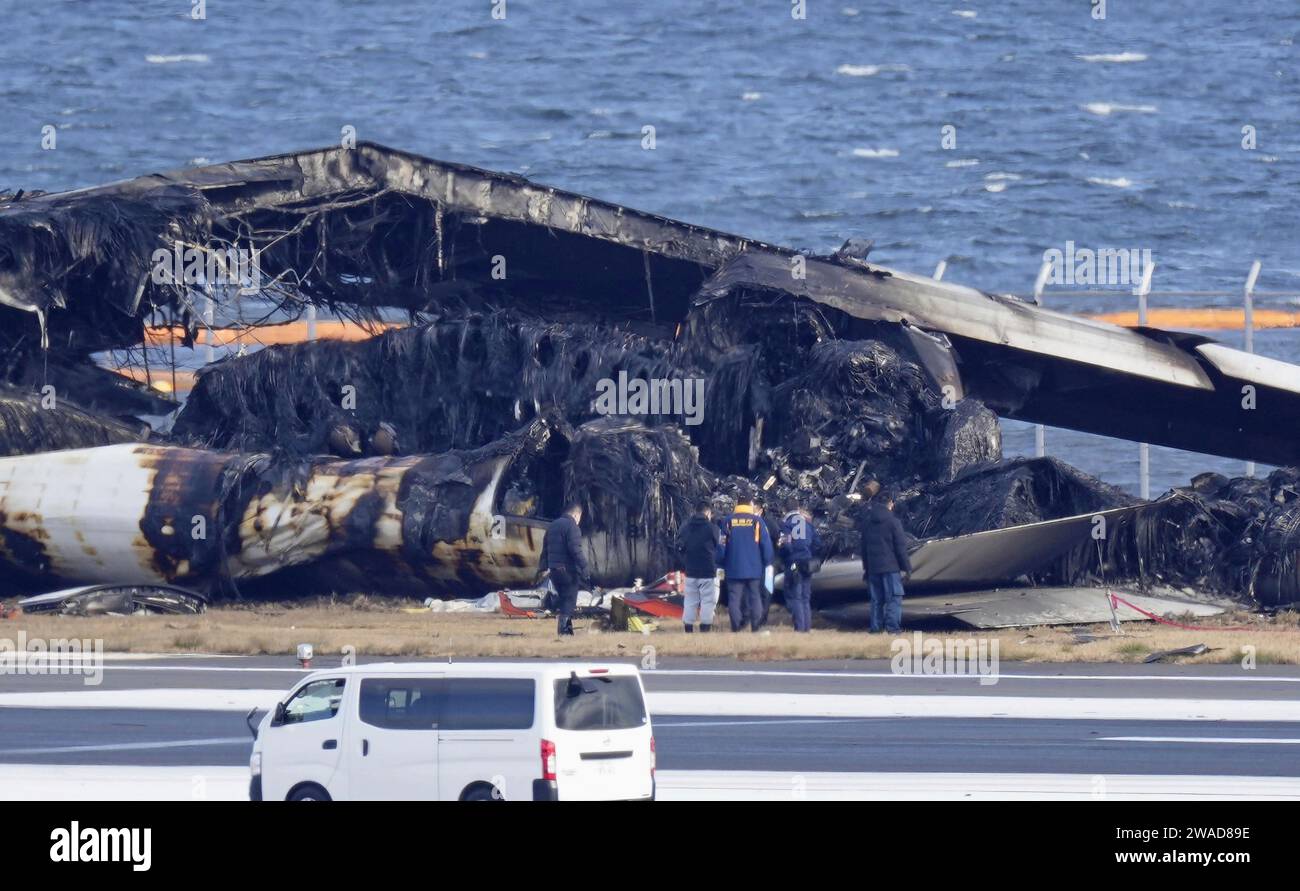 Police investigator look at the burn-out wreckage of Japan Airlines ...