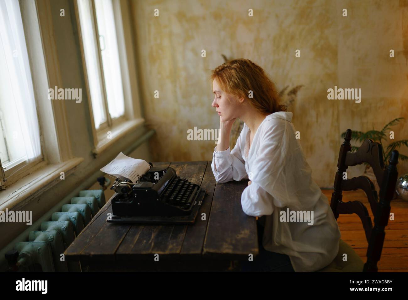 Side view of woman using vintage typewriter at home Stock Photo - Alamy