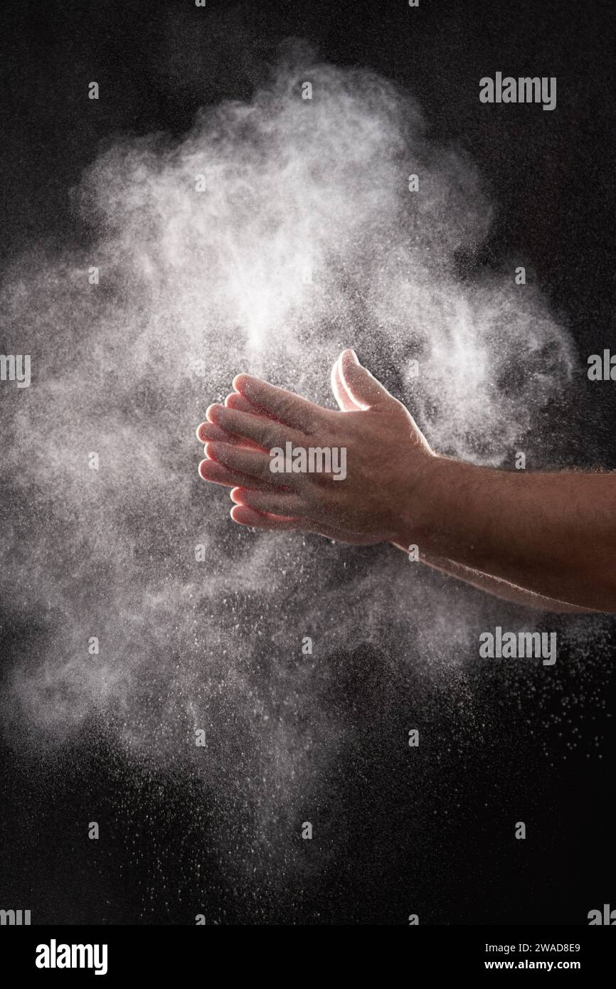 Baker dusting flour off his hands against black background Stock Photo ...