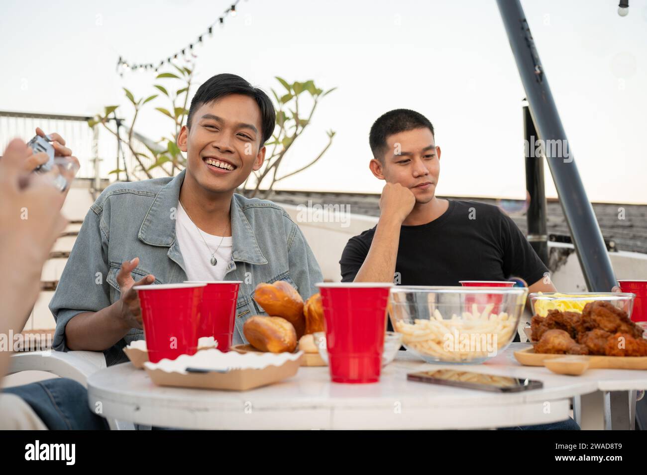 Group of happy young Asian friends partying on a rooftop bar restaurant ...