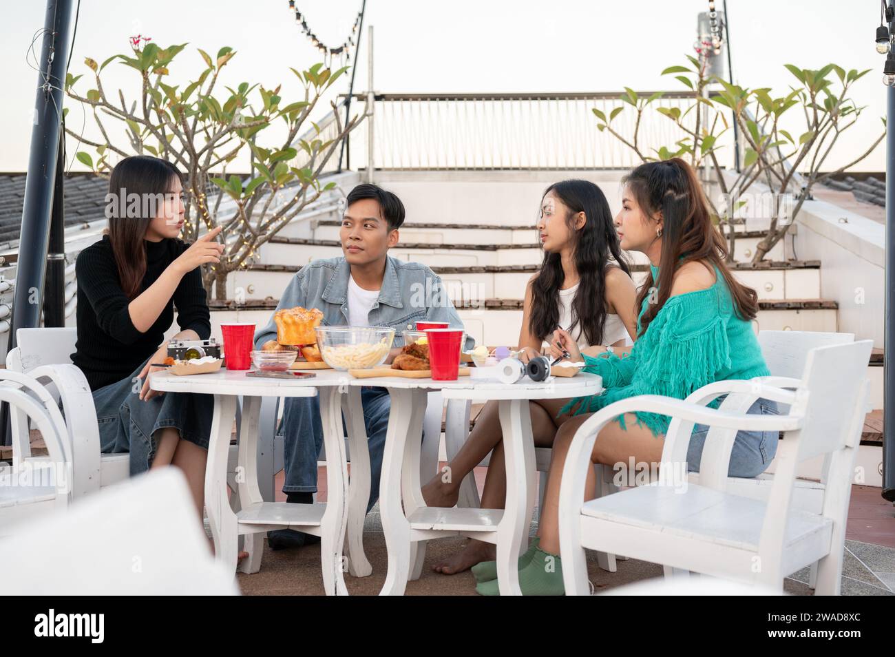 Group of happy young Asian friends partying on a rooftop bar restaurant ...