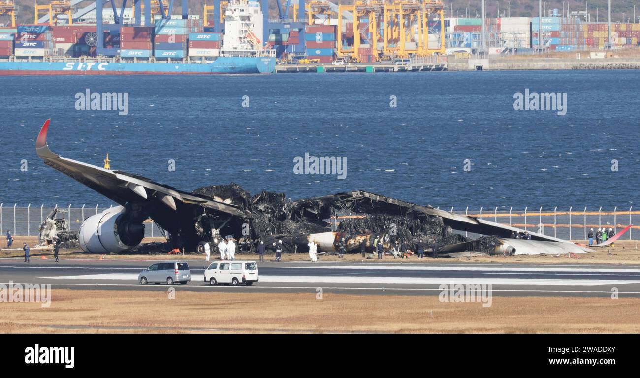 Police officers and others investigate a burnt Japan Airlines Flight ...