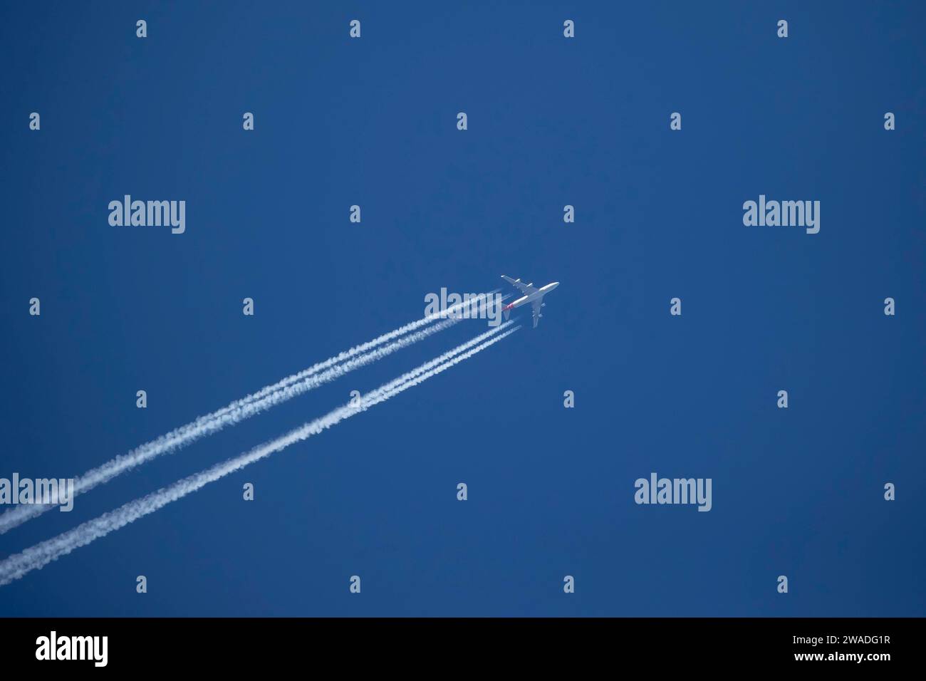 Boeing 747 aircraft flying across a blue sky leaving a contrail or ...
