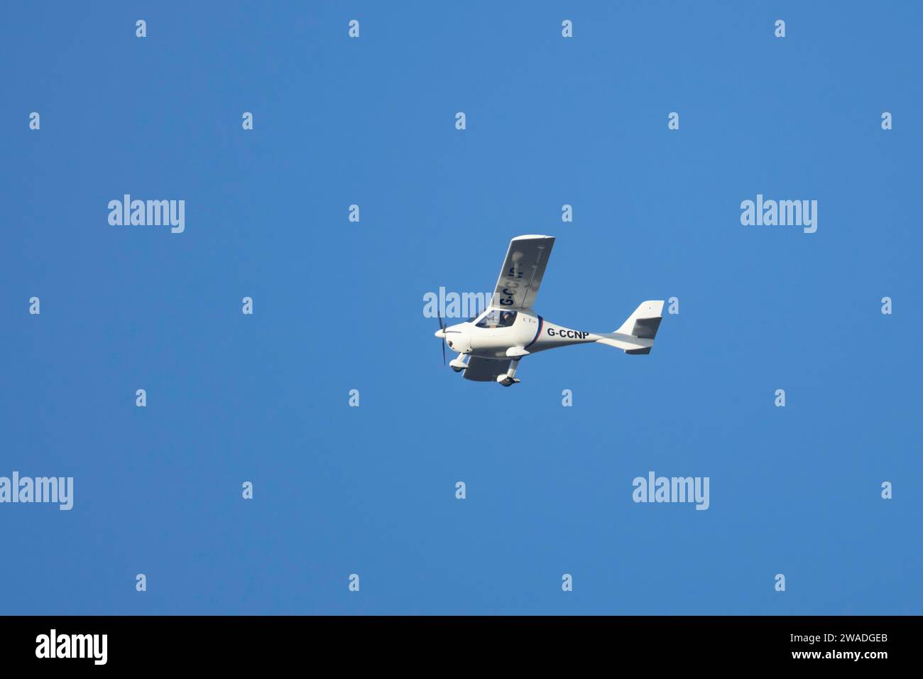 Flight Design CT2K small aircraft flying across a blue sky, England ...