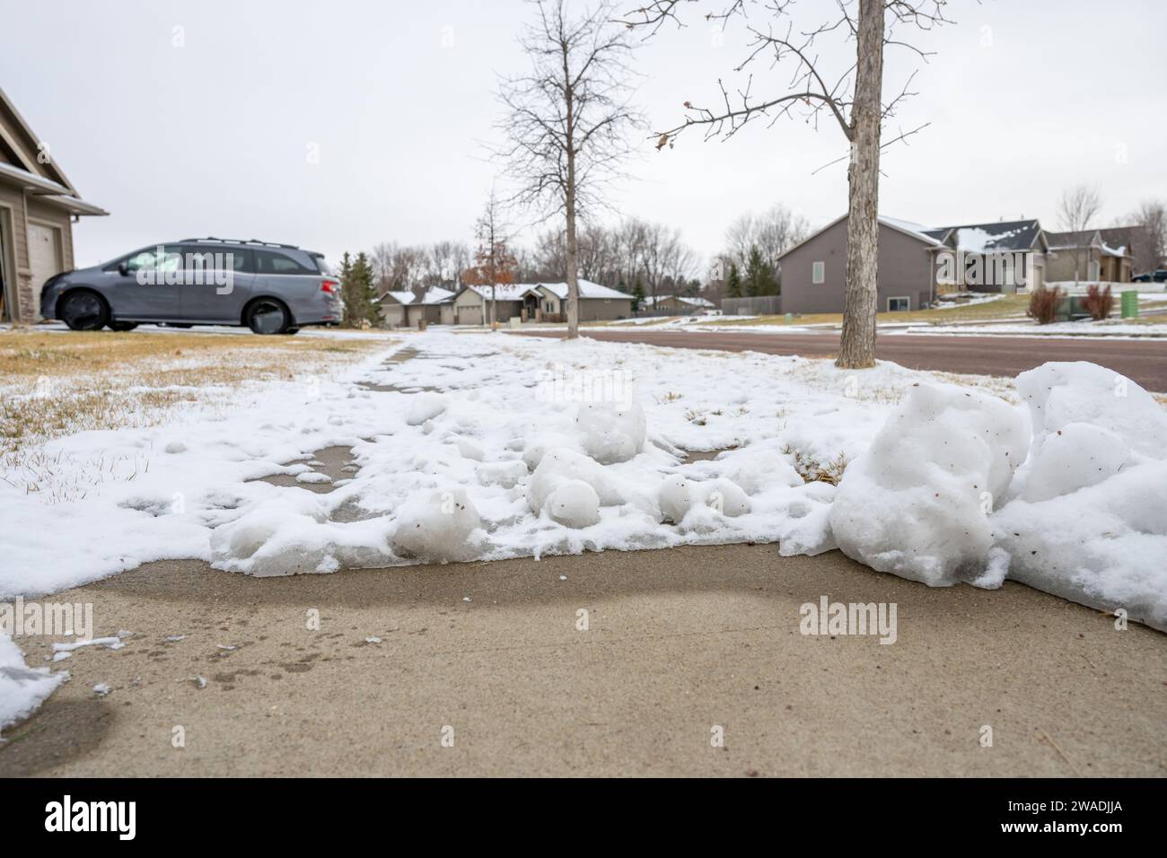 Residential sidewalk with section that has been cleared of snow next to ...