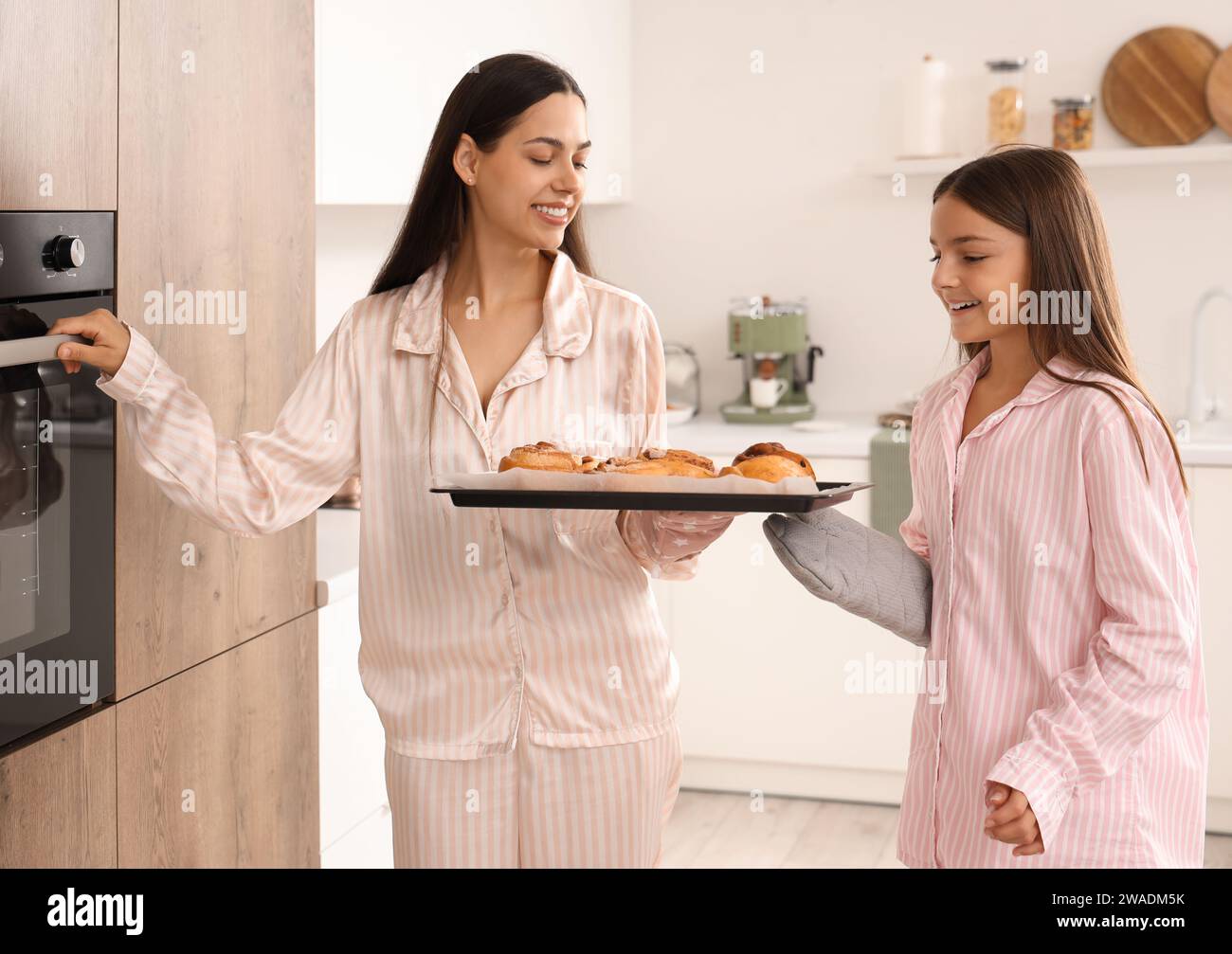 Happy mother with her little daughter and tasty buns in kitchen Stock ...