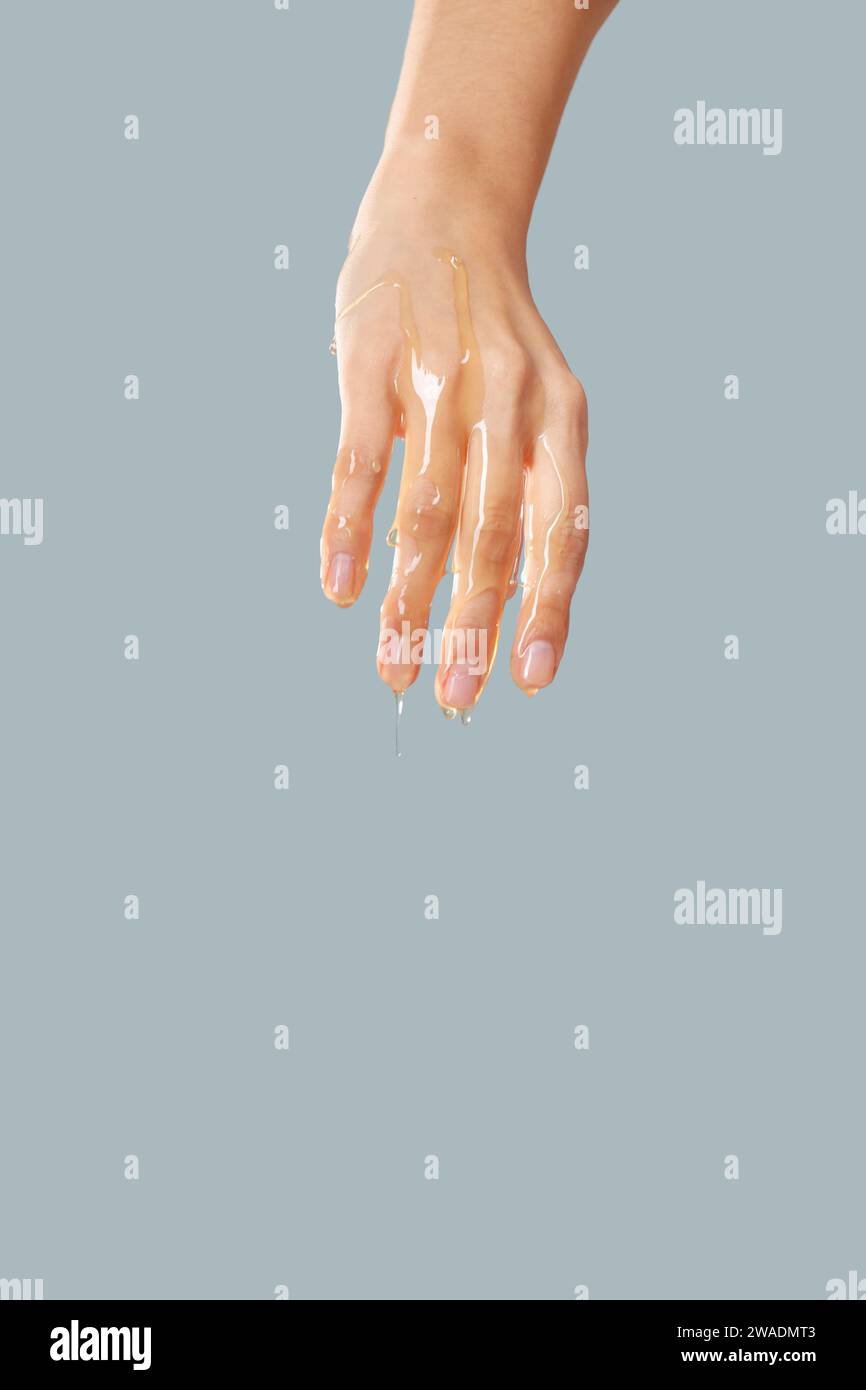 Woman with dripping honey on her fingers against grey background Stock ...
