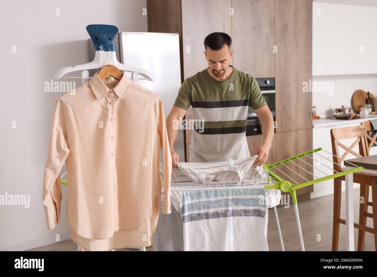 Man hanging clothes on rack in room with modern garment steamer Stock ...