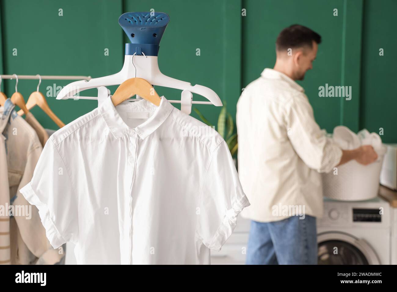 Man sorting clothes in laundry room with modern garment steamer Stock ...
