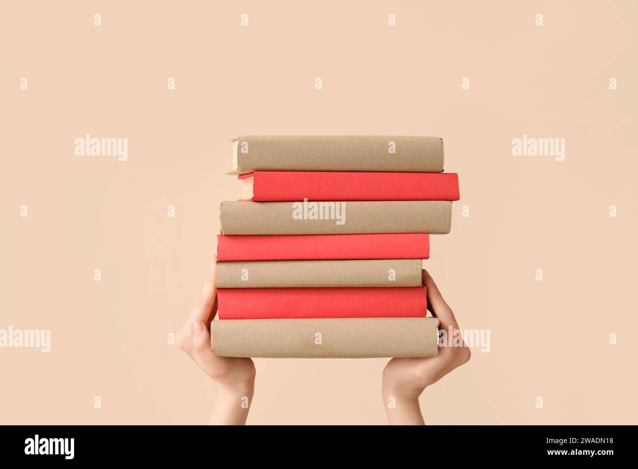 Hands holding stack of books on beige background Stock Photo - Alamy