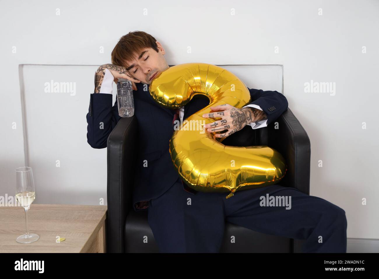 Drunk businessman with water and balloon sitting after New Year party ...