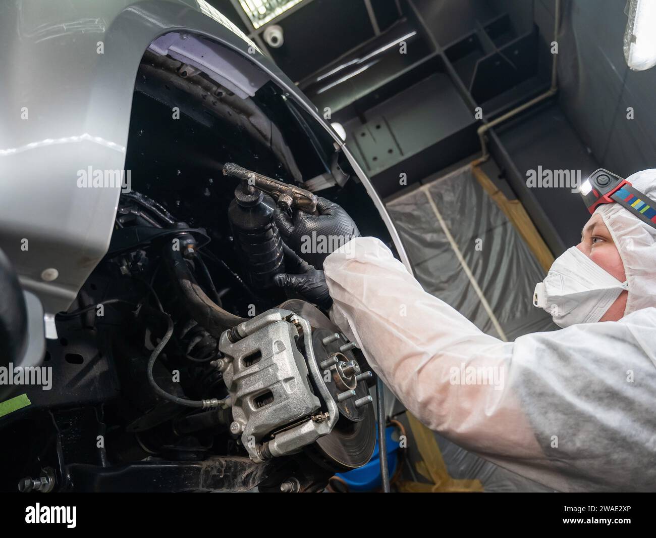 An auto mechanic applies anti-corrosion mastic to the underbody of a ...