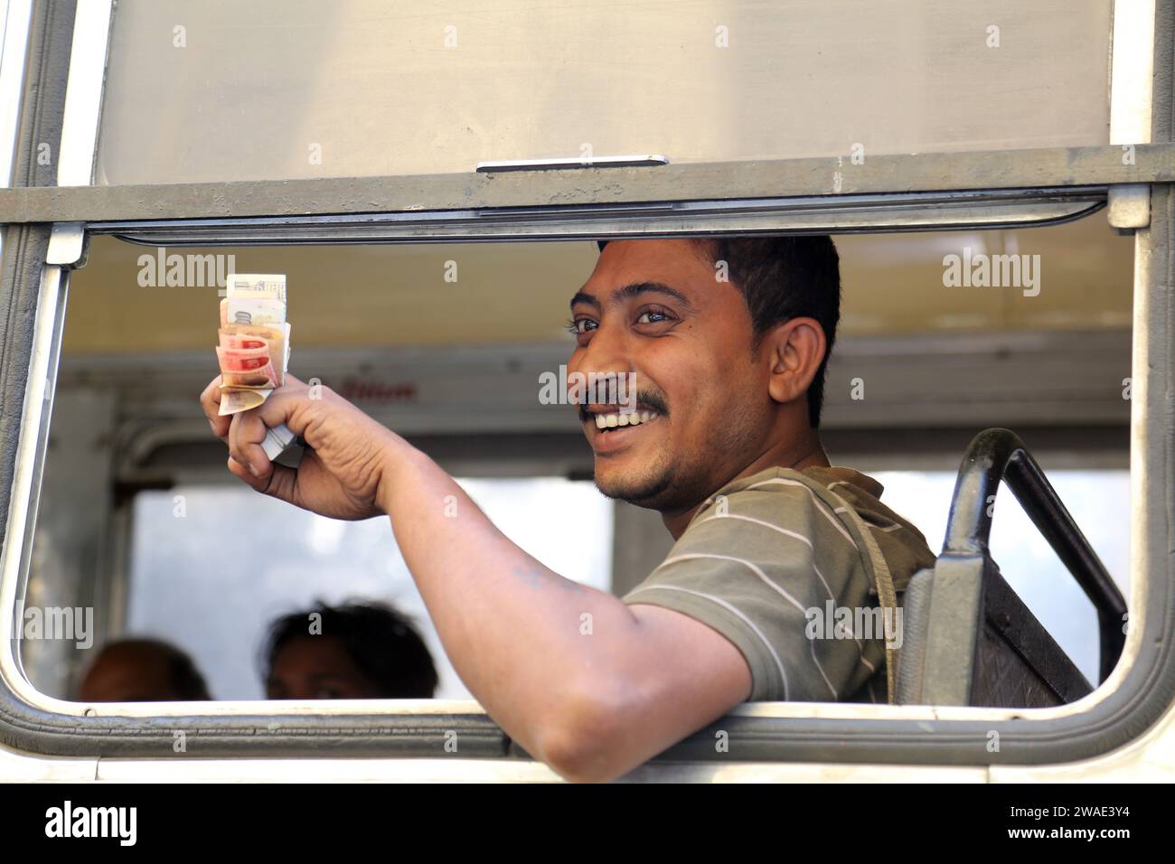 Bus conductor taking fares on a bus in Kolkata Stock Photo - Alamy