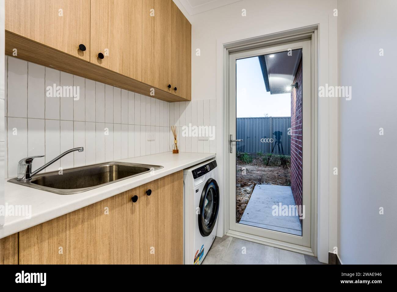 A nicely furnished kitchen with a wooden under sink, washing machine ...