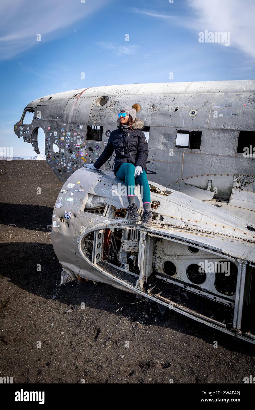 An adult male is sitting on the side of an airplane, suspended in mid ...